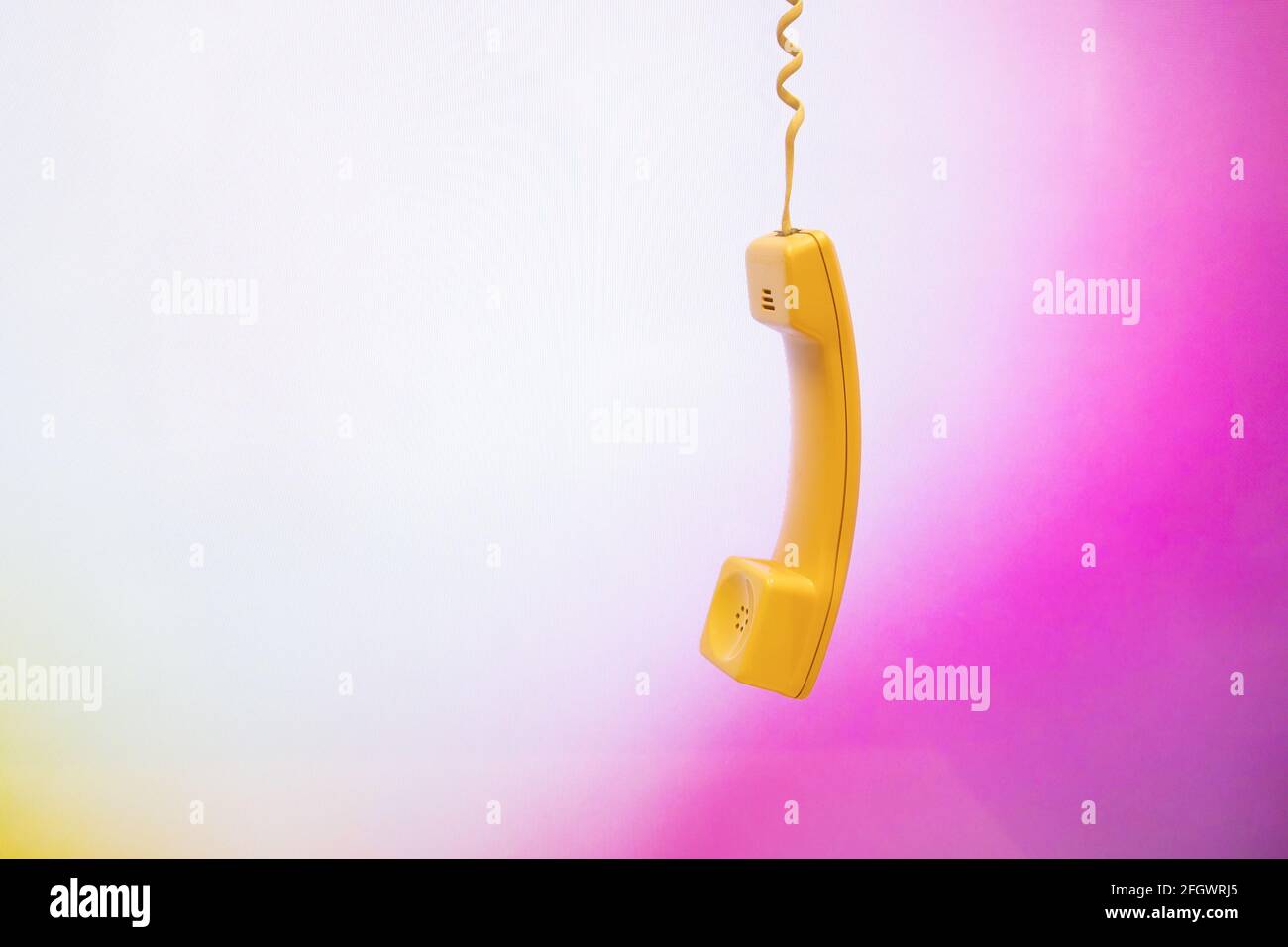 Telephone handset or receiver hanging from above on pinky background ...