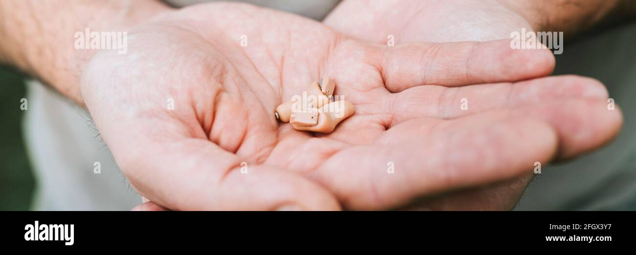 small intra channel hearing aids device in a man's hands. banner Stock ...