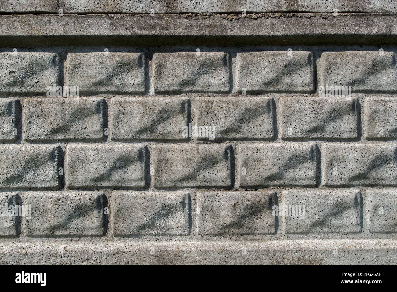 A fragment of gray concrete relief wall or fence imitating several rows ...