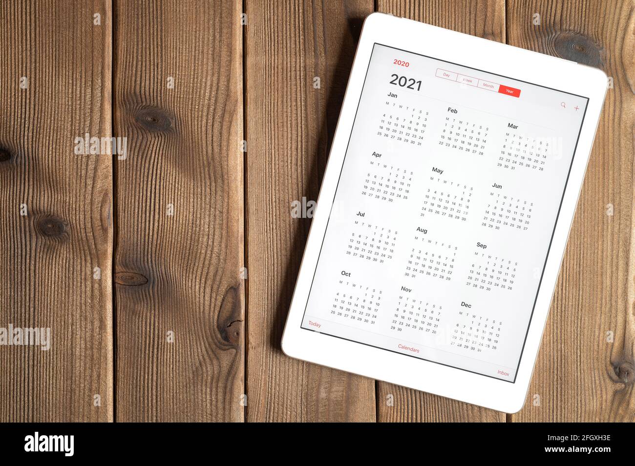 a tablet with an open calendar for 2021 year on a wooden boards table ...