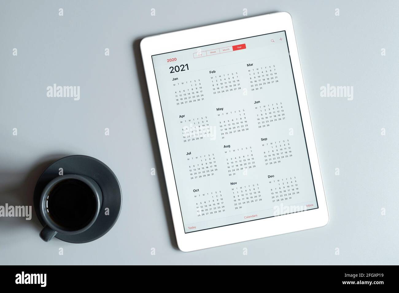 a tablet with an open calendar for 2021 year and a cup of coffee on a ...