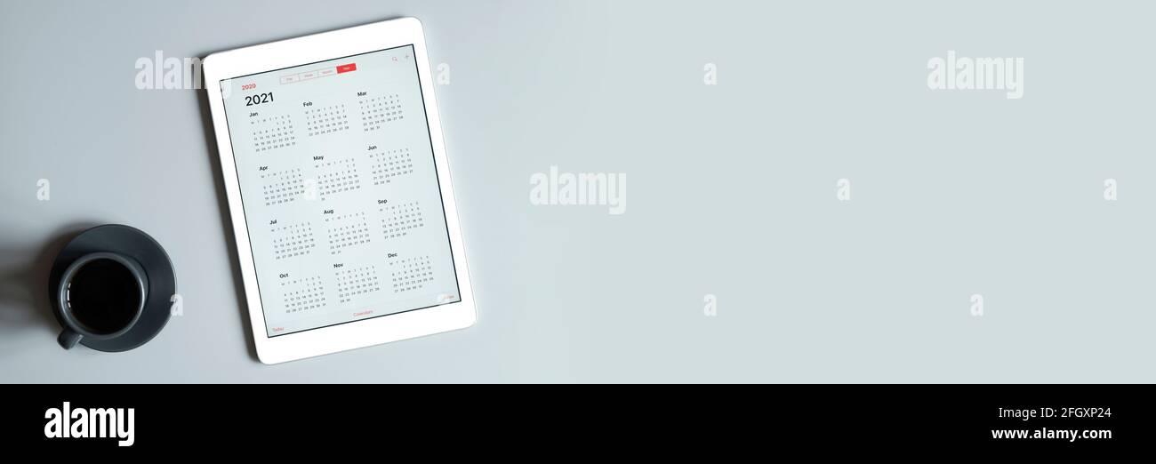 a tablet with an open calendar for 2021 year and a cup of coffee on a ...