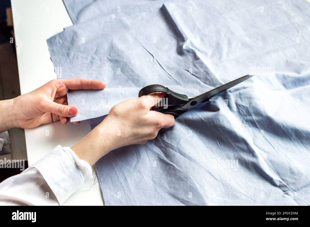 Woman cuts fabric with scissors for tailoring Stock Photo - Alamy