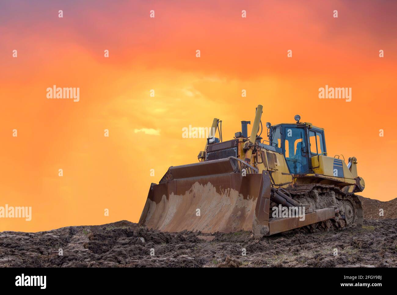 Dozer on earthmoving at construction site on sunset background ...