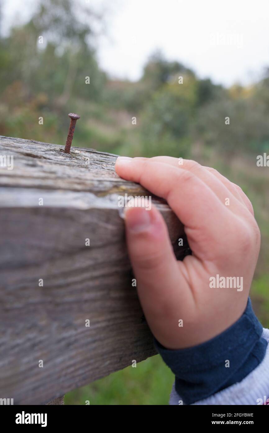 Child boy hand grabbing a board with rusty nail near. Selective focus ...