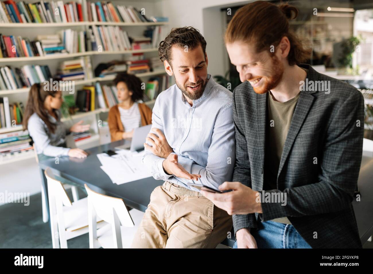Happy young business people colleagues talking working in office Stock ...