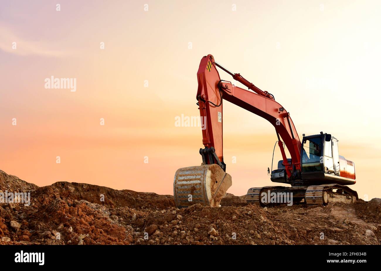 Excavator during earthmoving work at open-pit mining on sunset ...