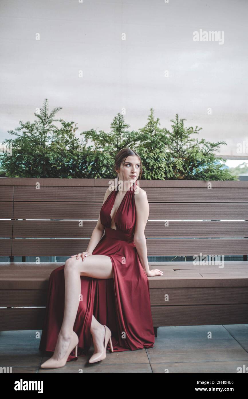 A vertical shot of an elegant young woman wearing a red dress with high ...