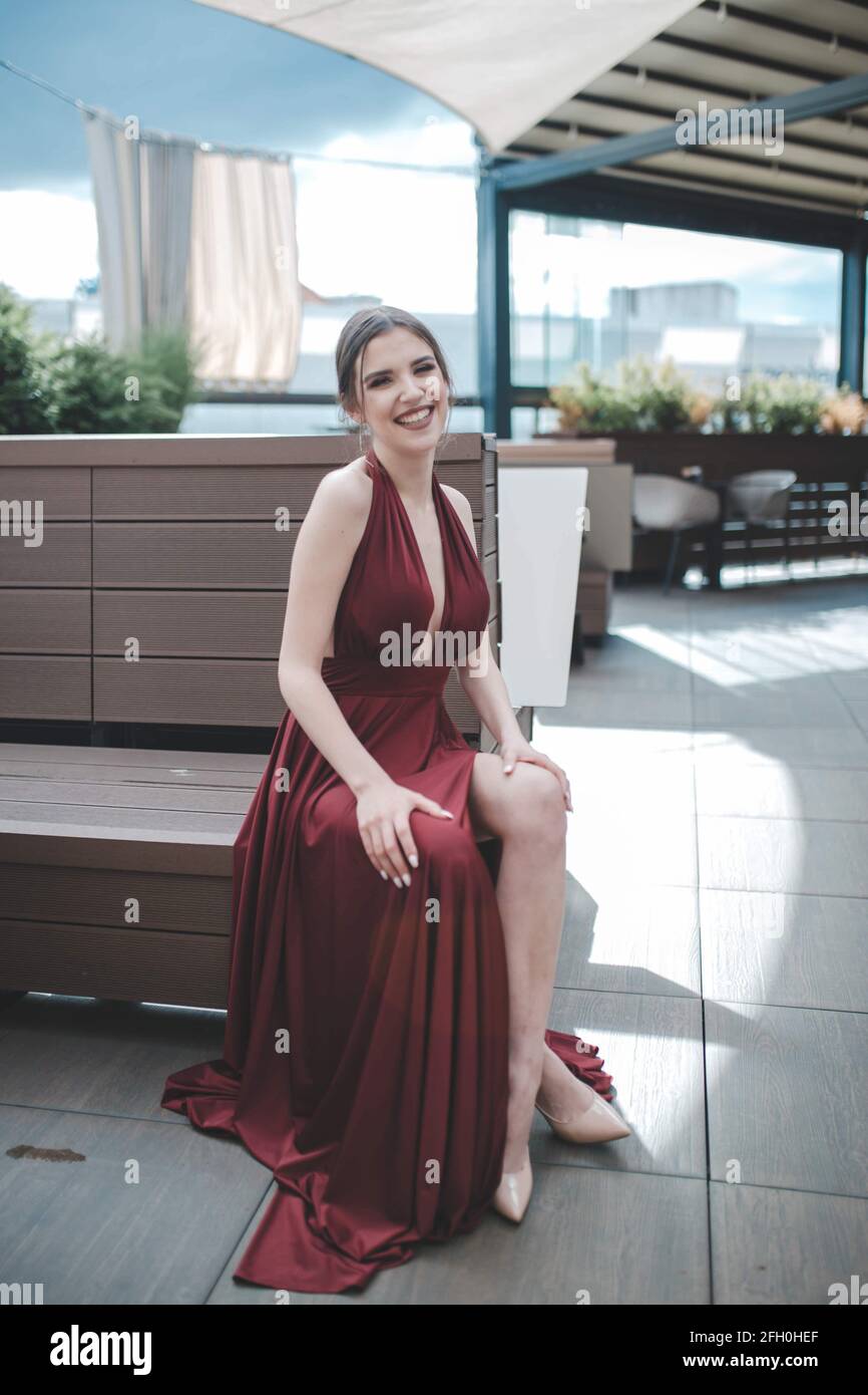 A cheerful adult woman wearing a red dress with high heels and sitting ...