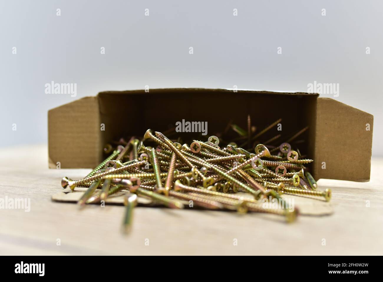 Self-tapping screws in a cardboard box on wooden table. Screw for ...