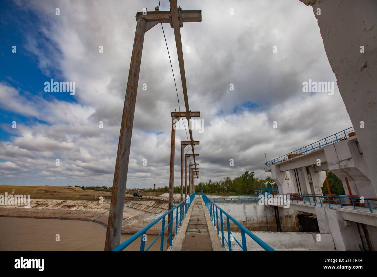 Dam on Shardara river. Concrete bridge, water shutter equipment. Yellow ...