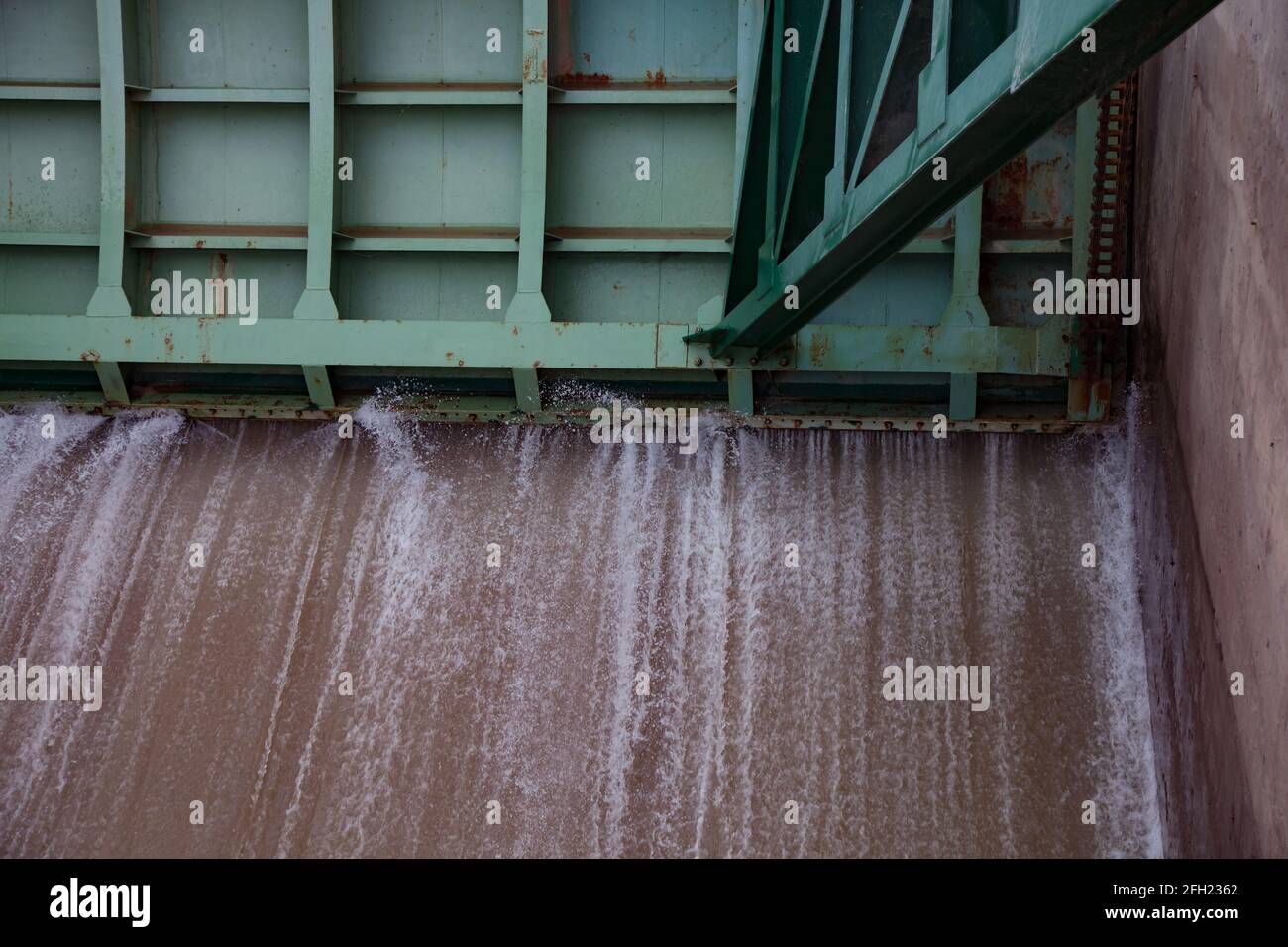 Aklak dam on Shardara river. Half-open green steel water shutter of dam ...