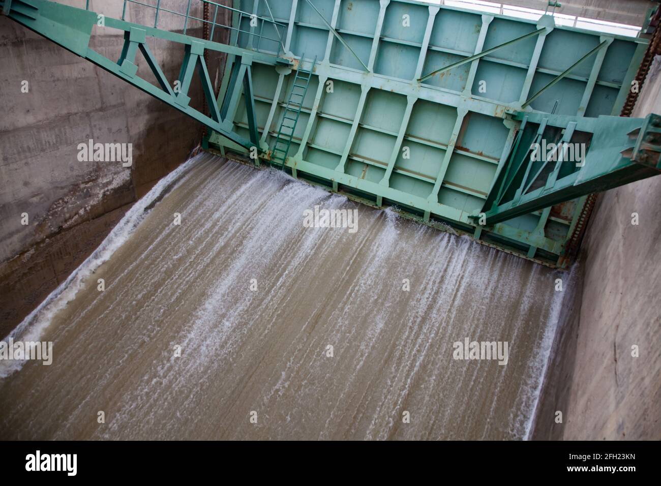 Aklak dam on Shardara river. Half-open green steel dam shutter. Strong ...