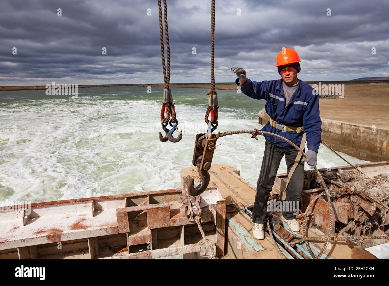 Kok-aral,Kazakhstan:Small Aral Sea dam.Worker lifts water shutter ...