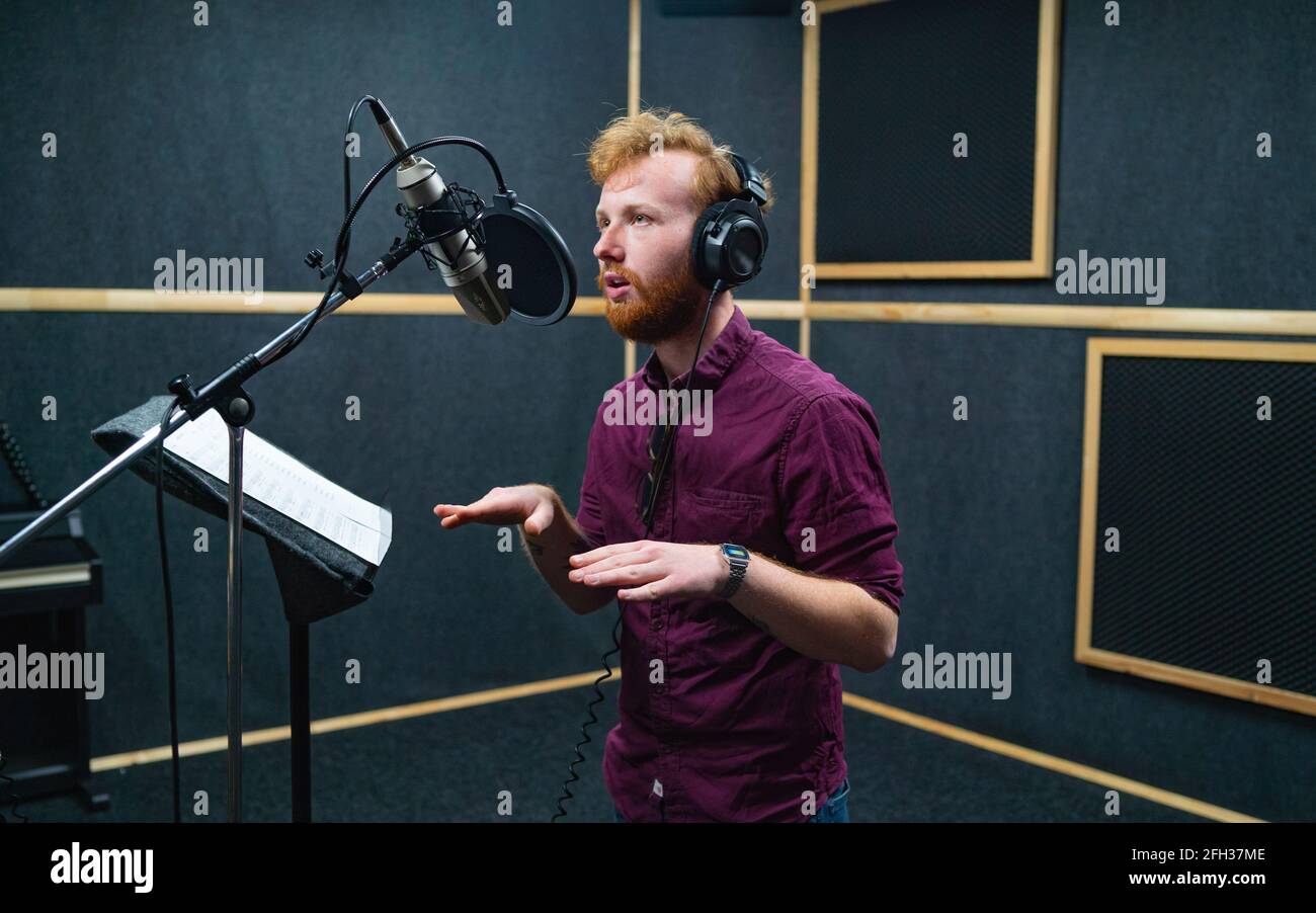 Expressive bearded man with curly ginger hair in headphones at ...