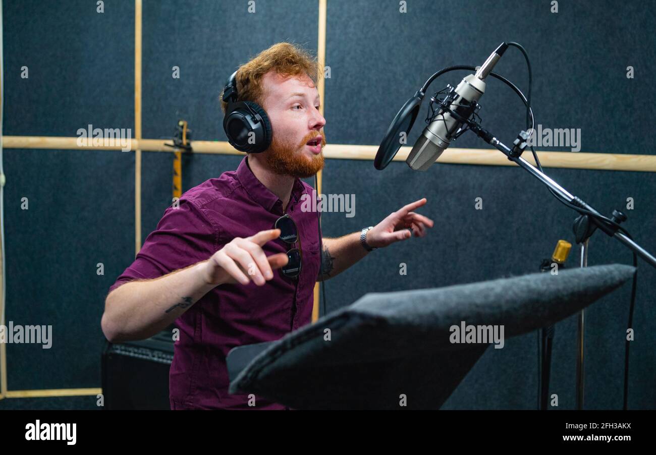 Side view of young male singer with headphones performing song near ...