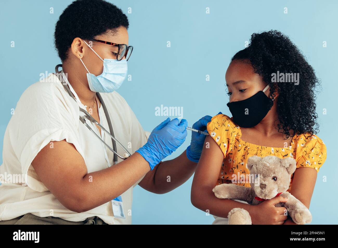 Pediatrician giving injection in arm of a girl. Doctor giving vaccine ...