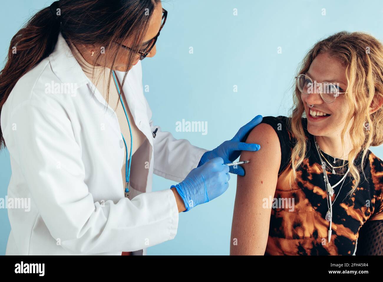 Woman getting injection on arm from a female doctor. Woman getting ...