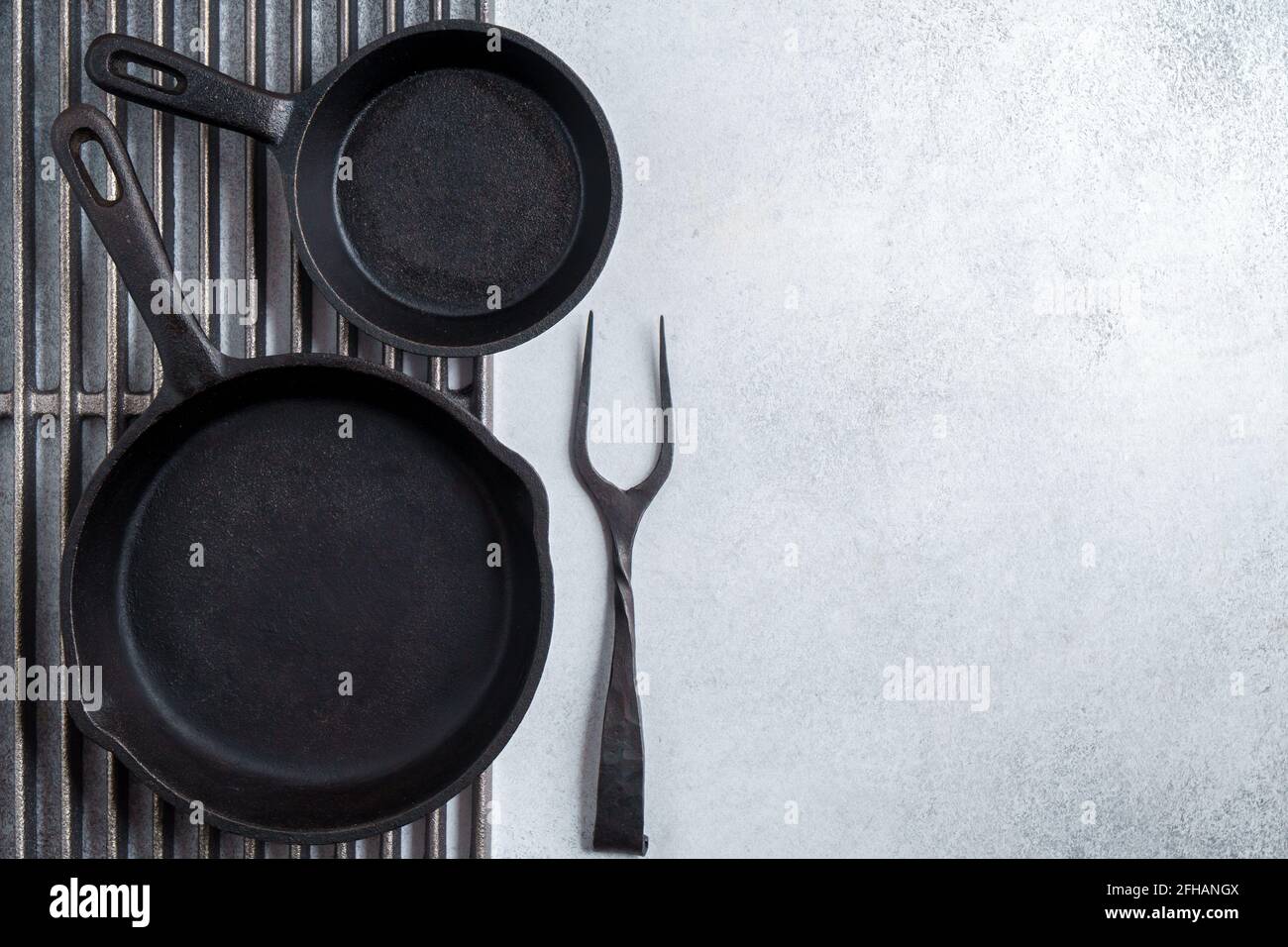 Pair of cast iron pans on grill grates and fork with copy space Stock ...