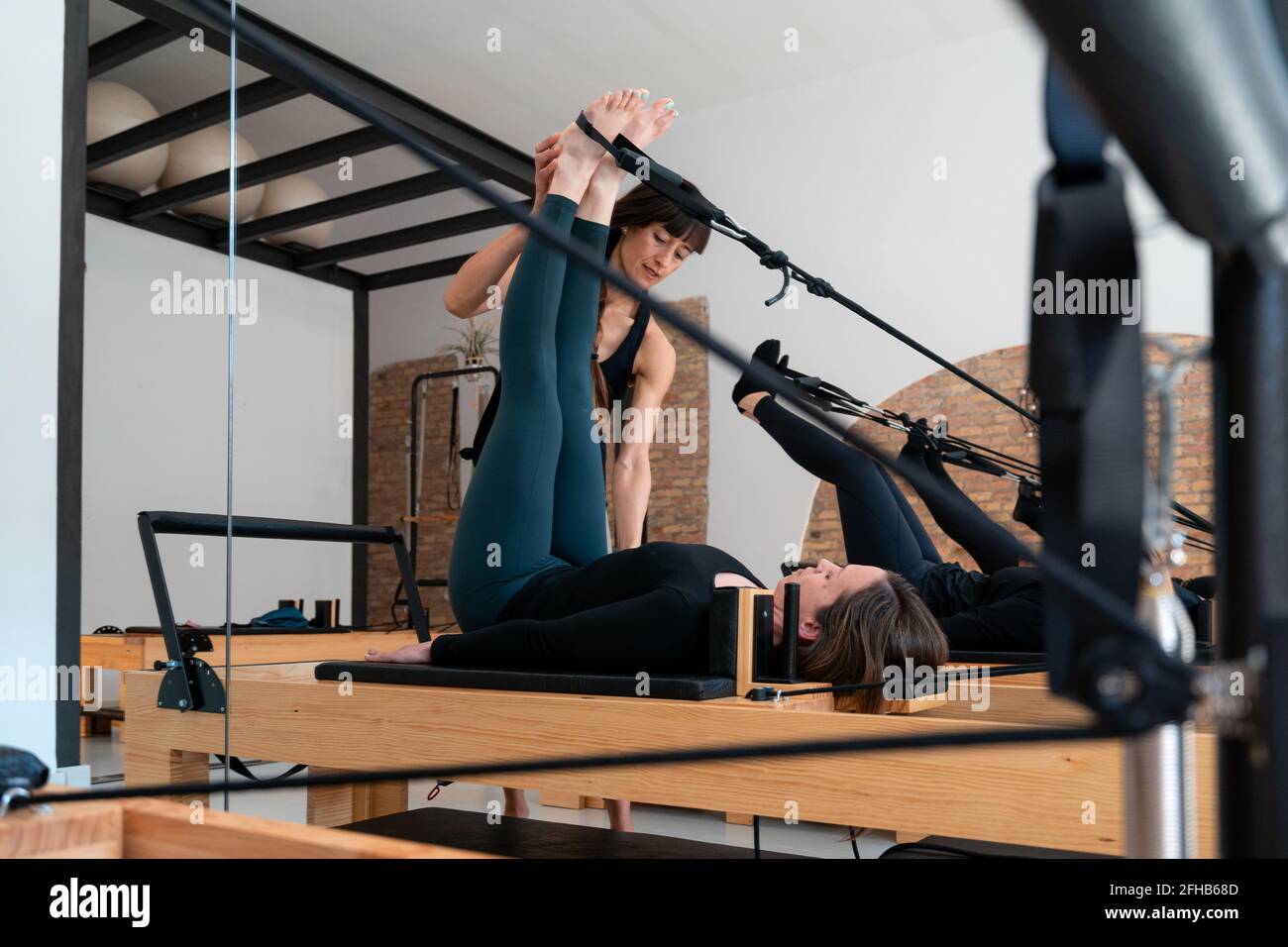 Flexible female stretching legs with help of personal instructor while ...