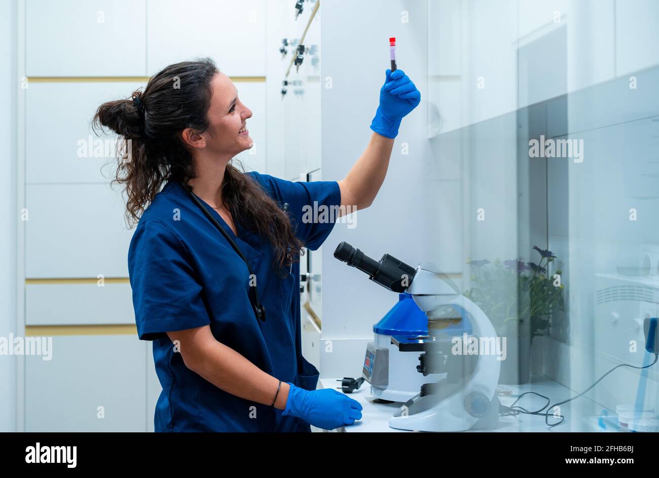 Side view of content female veterinarian in uniform with test tube ...