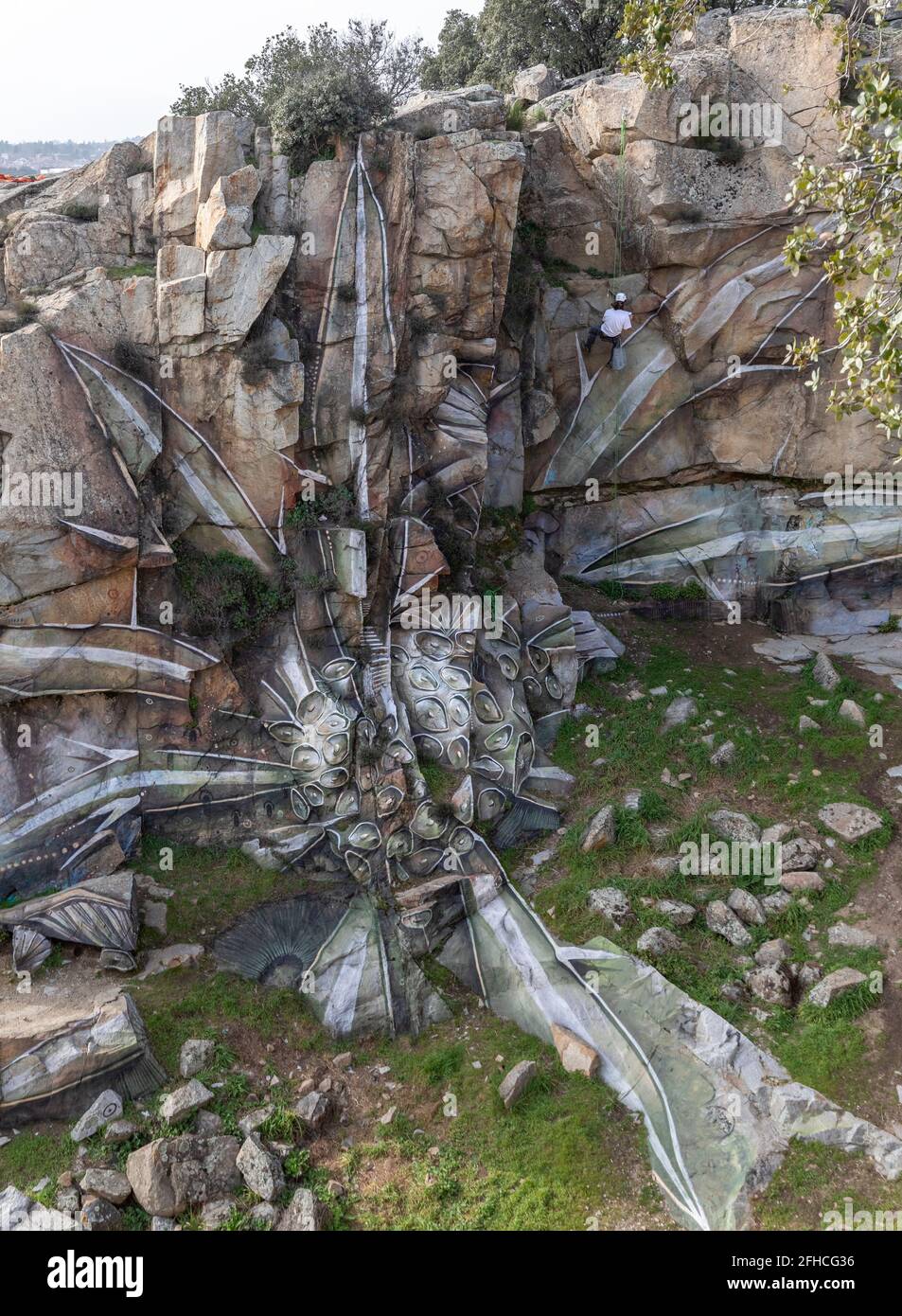 Drone view of man in helmet hanging on rope while painting graffiti on ...