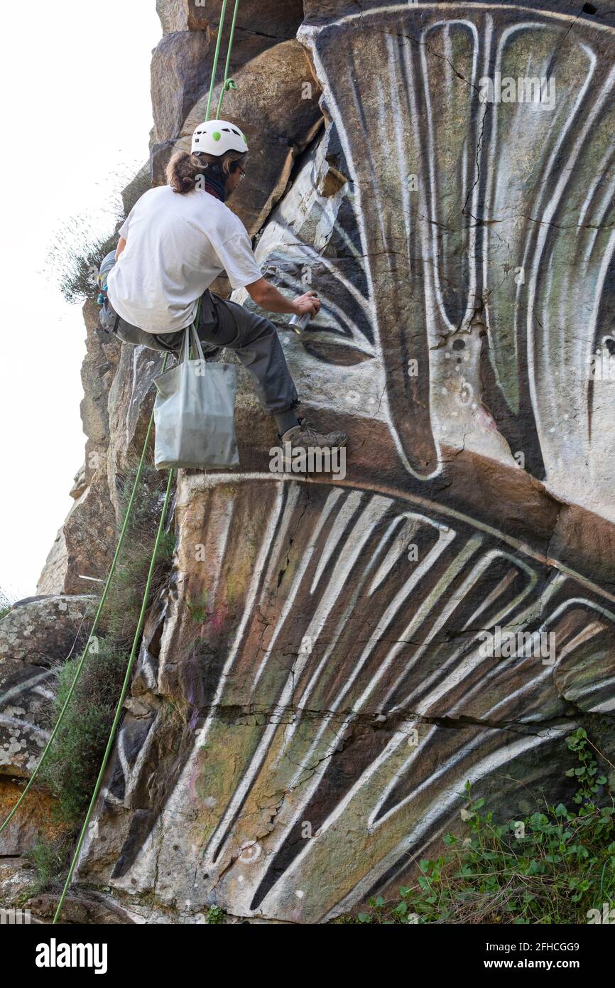 Back view full body of painter with spray paint making graffiti hanging ...
