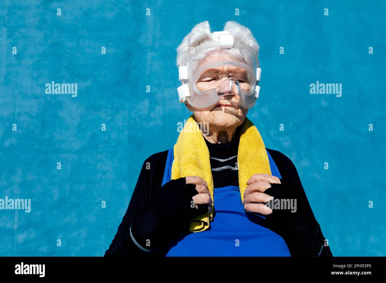 Serious mature female in activewear in protective boxing head guard ...