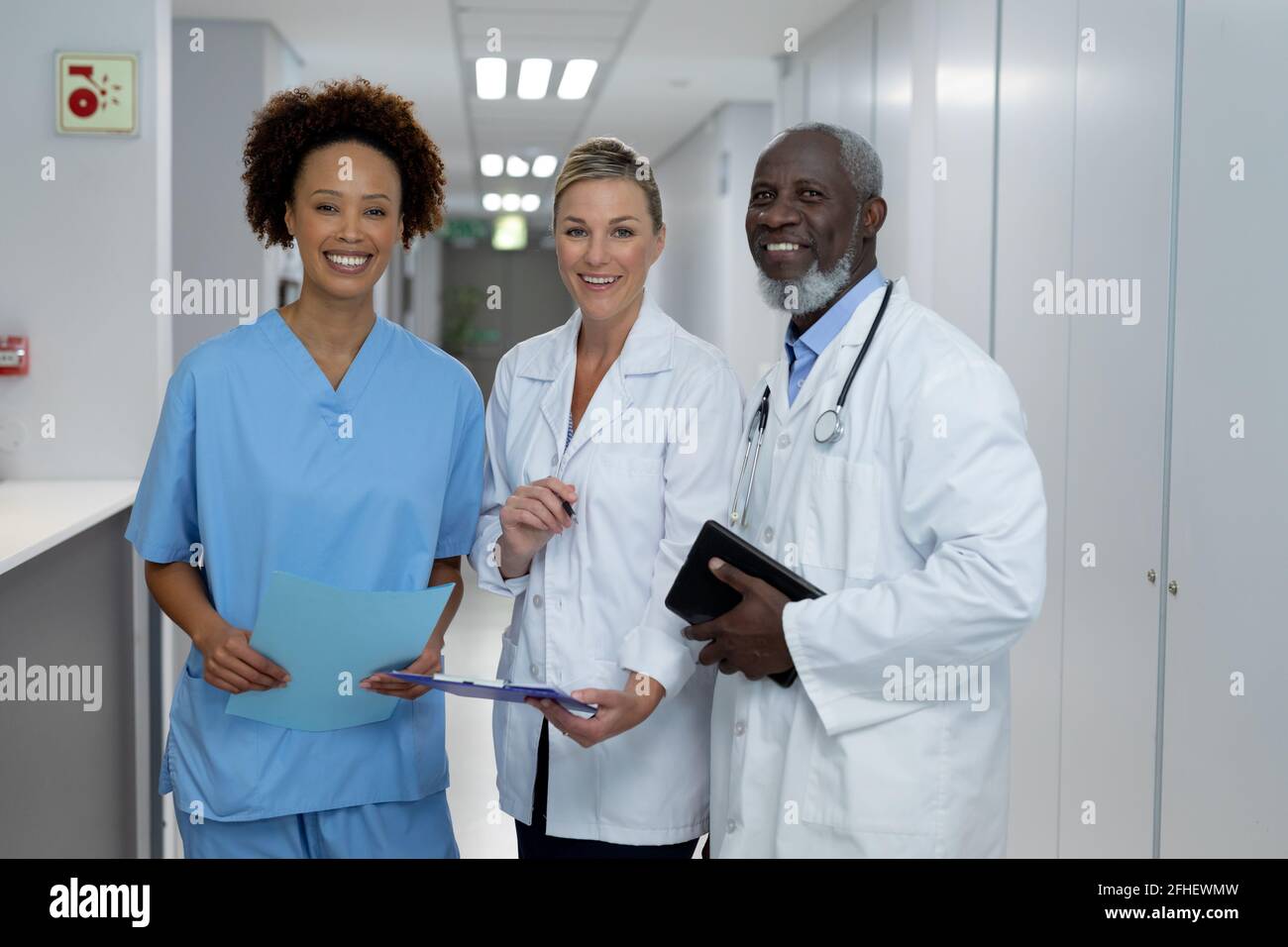 Portrait of three diverse male and female doctors standing in hospital ...