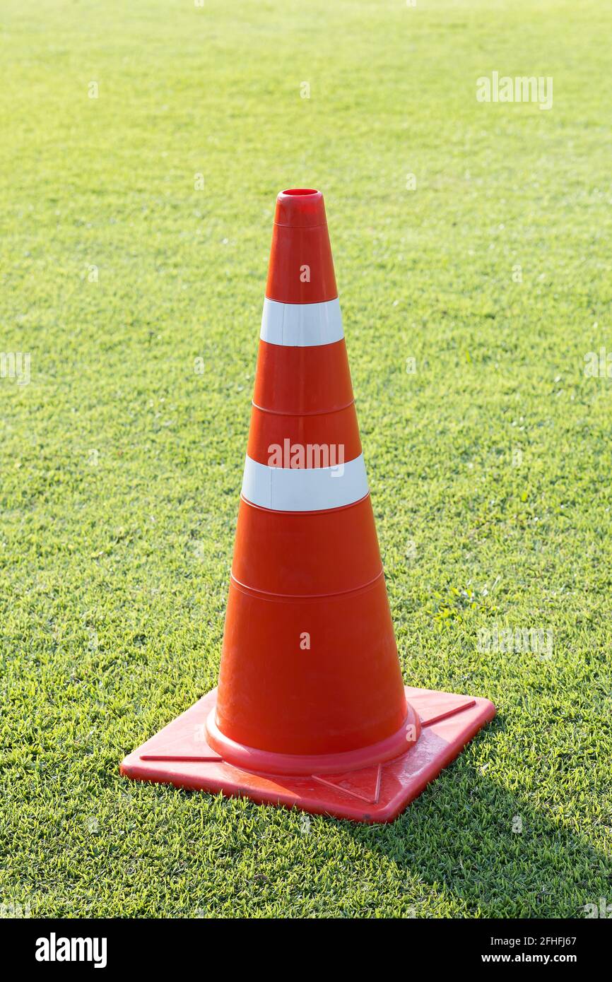 red plastic traffic cone on green grass field lawn with silver color ...