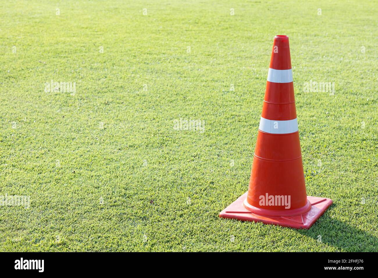 red plastic traffic cone on green grass field lawn with silver color ...