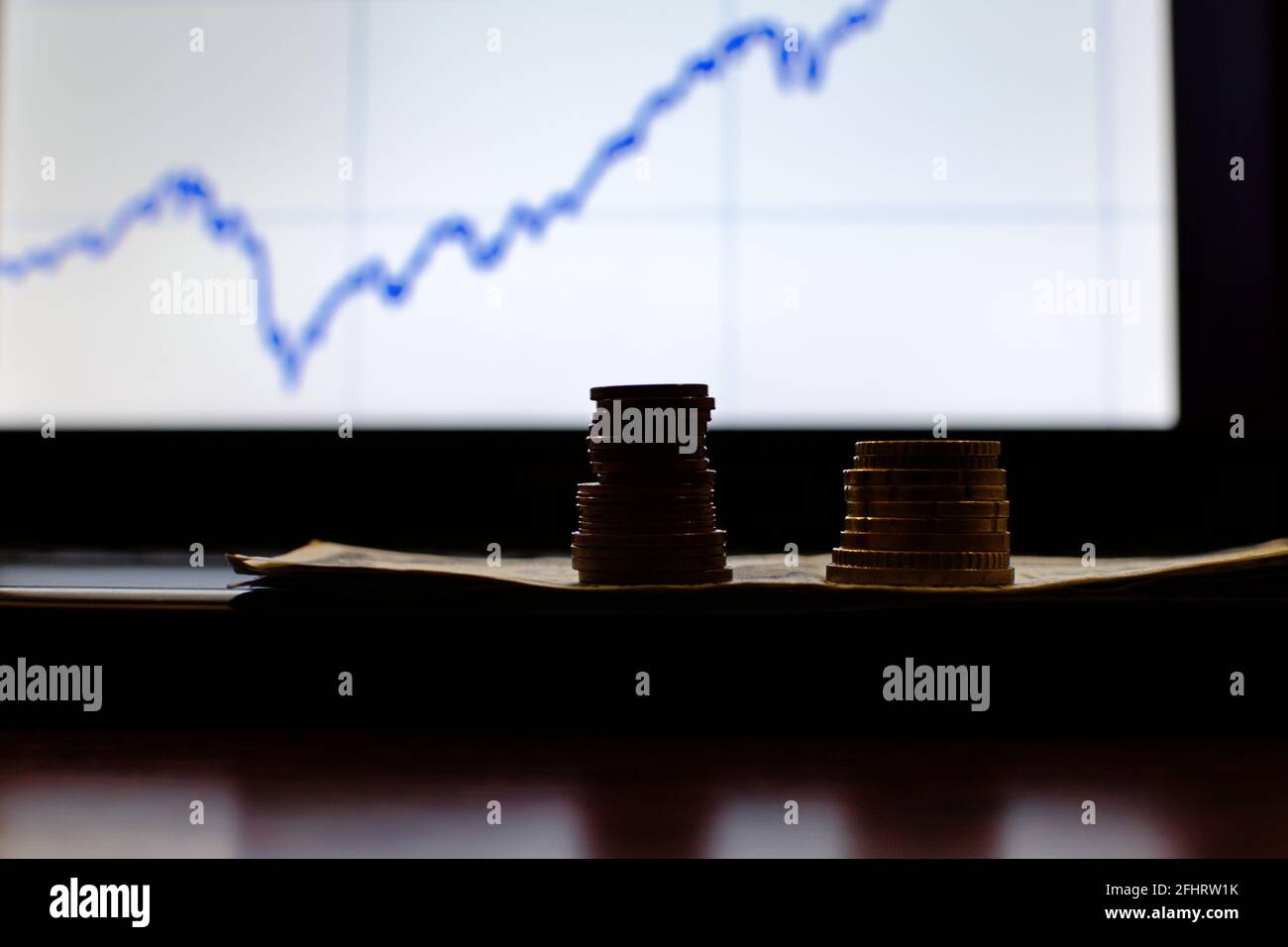 stacks of coins on blurred computer screen background with stock chart ...
