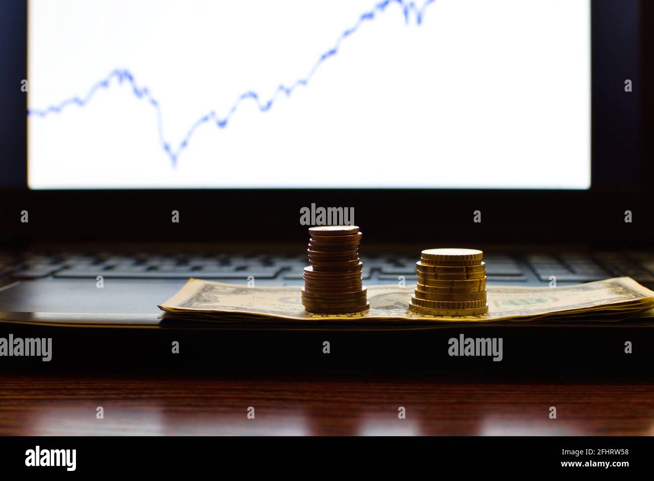 stacks of coins on blurred computer screen background with stock chart ...