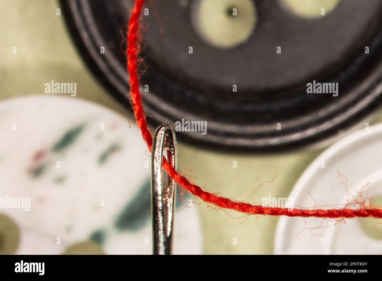 a red thread is threaded into a sewing needle Stock Photo - Alamy