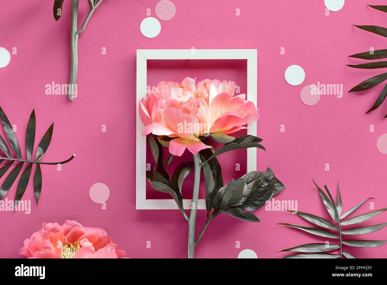 Pink peony in white frame, palm leaves. Creative flat lay, top view on ...