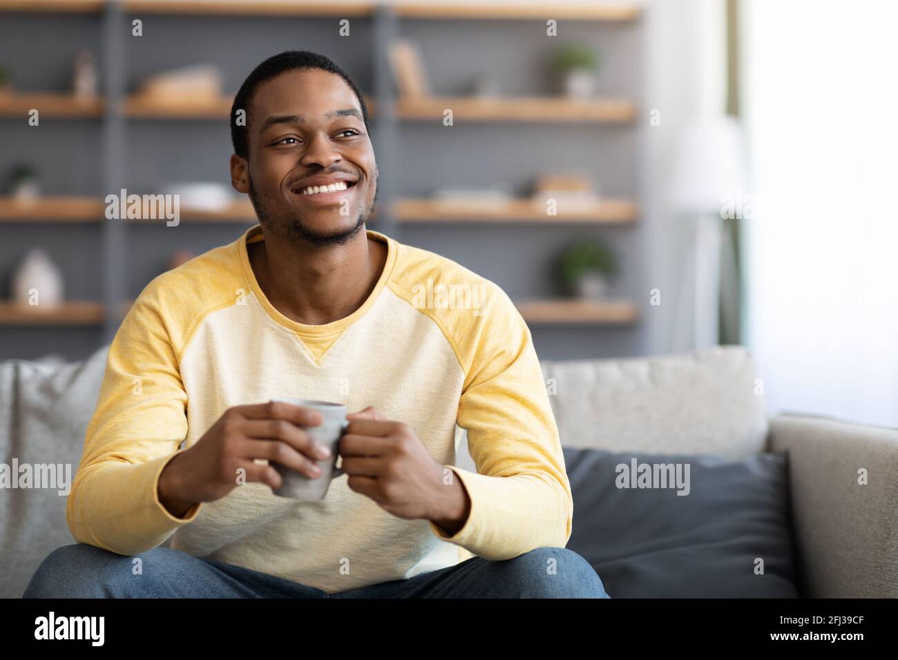 Relaxed handsome black man drinking coffee in living room Stock Photo ...