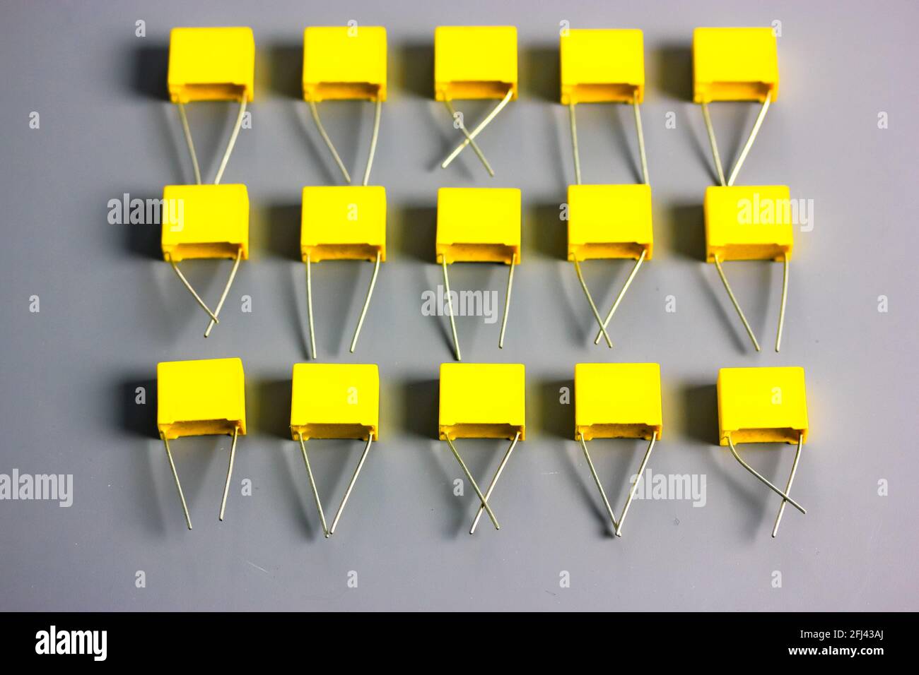 Yellow film capacitors on gray background top view. Electronic radio ...