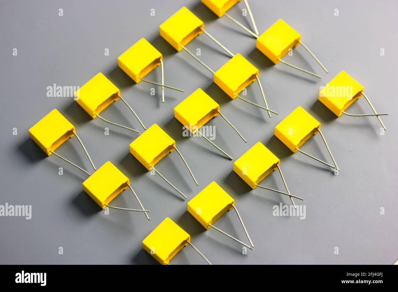 Yellow film capacitors on gray background top view. Electronic radio ...