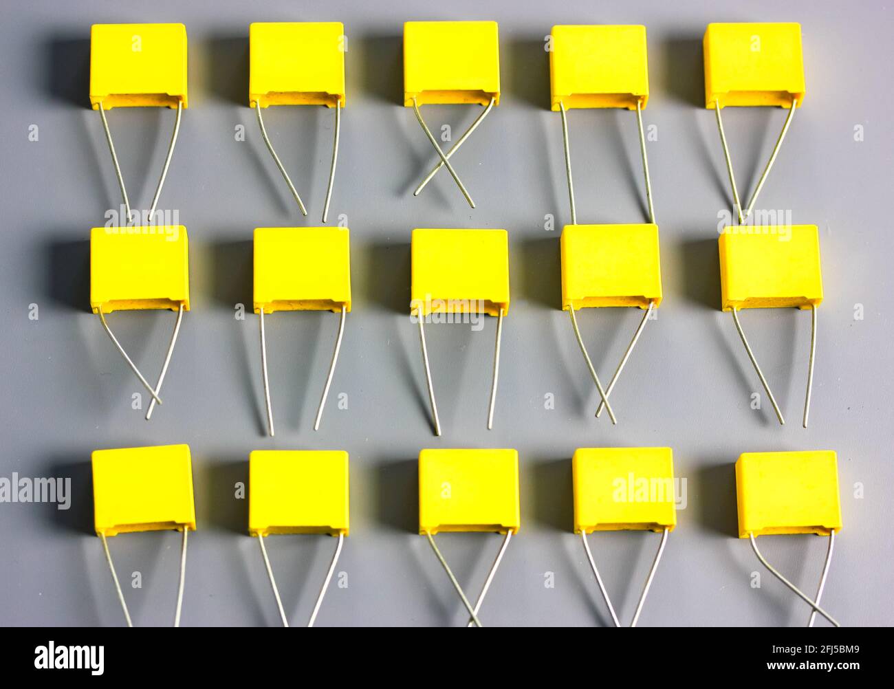 Yellow film capacitors on gray background top view. Electronic radio ...