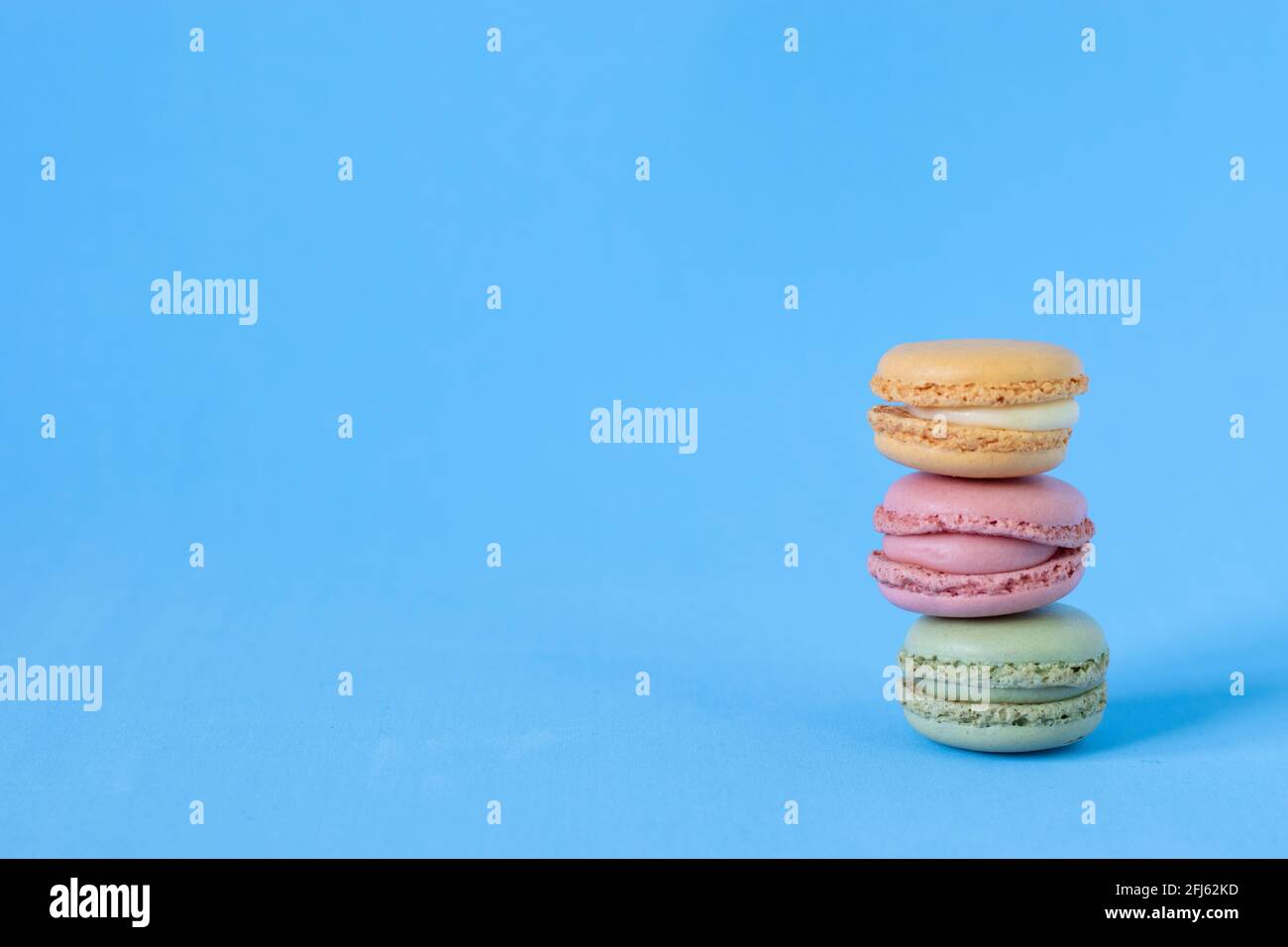 Three Macaroons, yellow, pink and green on green background Stock Photo ...