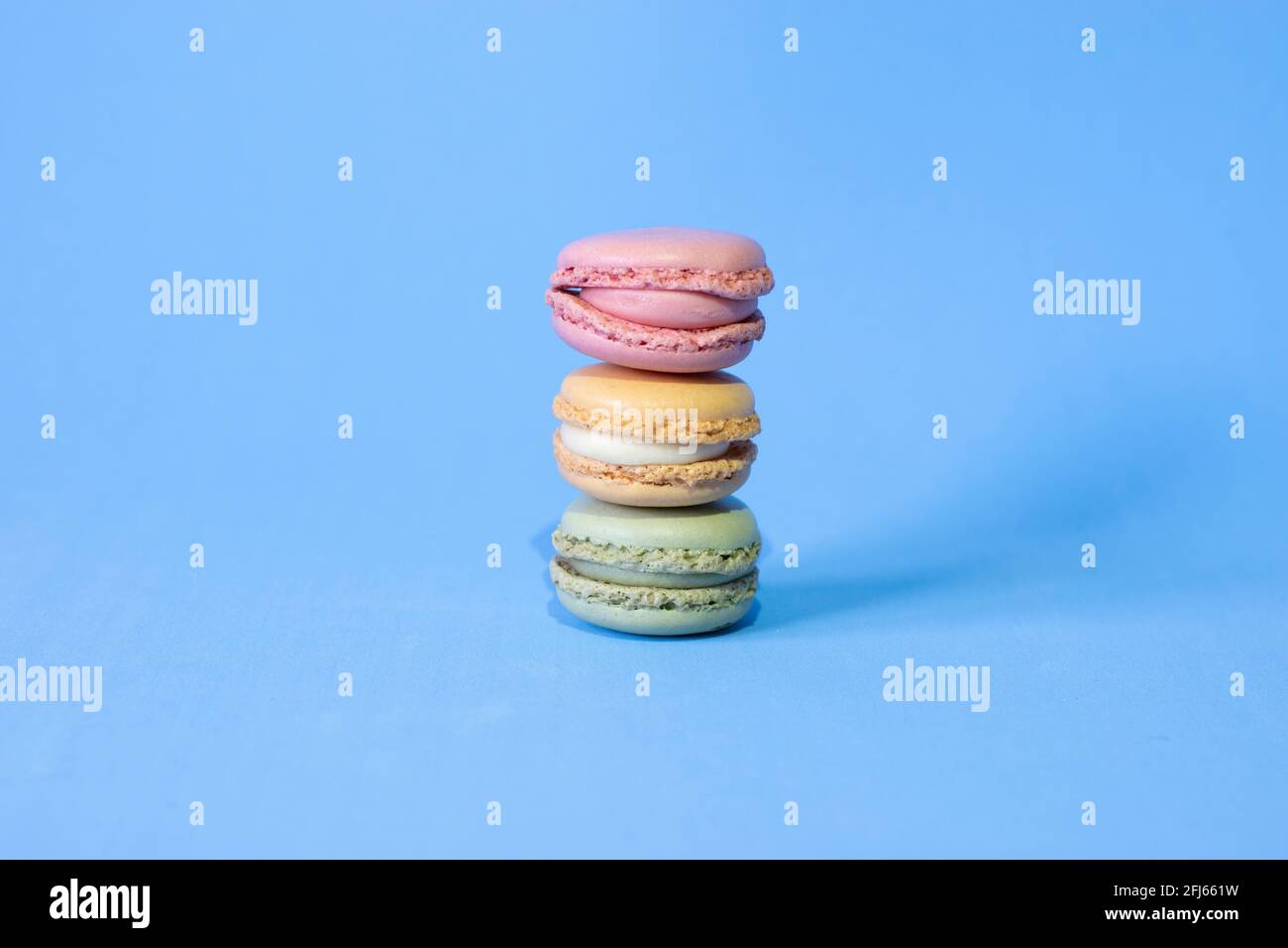 three coloured macarons on a blue background Stock Photo - Alamy