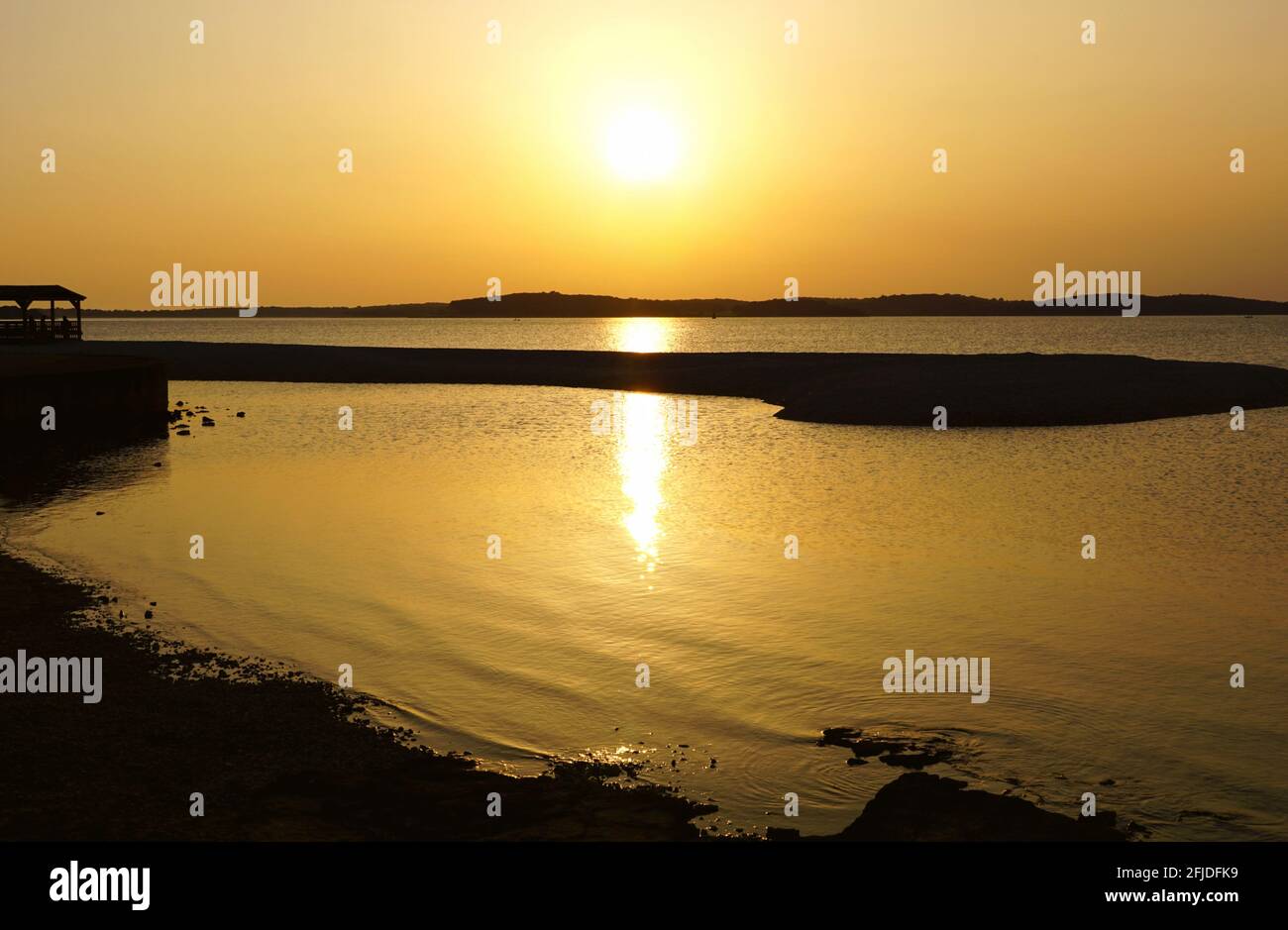 Sun at sunset above beautiful sea lagoon enlightened in gold color tone ...