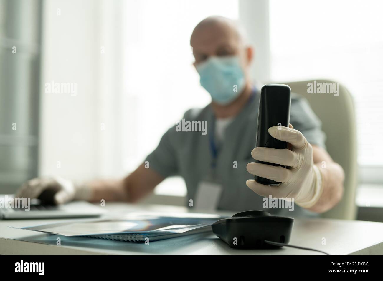 Chief surgeon in gloves sitting at desk and using computer while ...