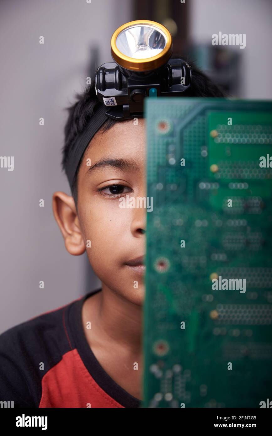 Little boy holding the motherboard, studying computer component at home ...