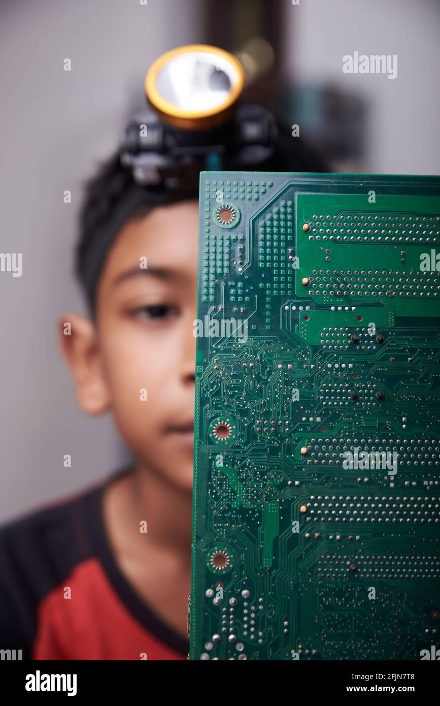 Little boy holding the motherboard, studying computer component at home ...
