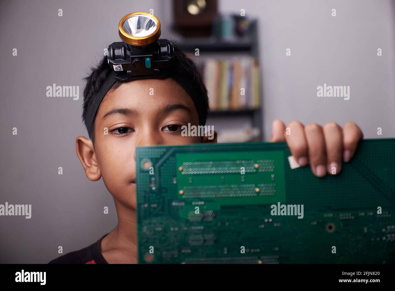 Little boy holding the motherboard, studying computer component at home ...
