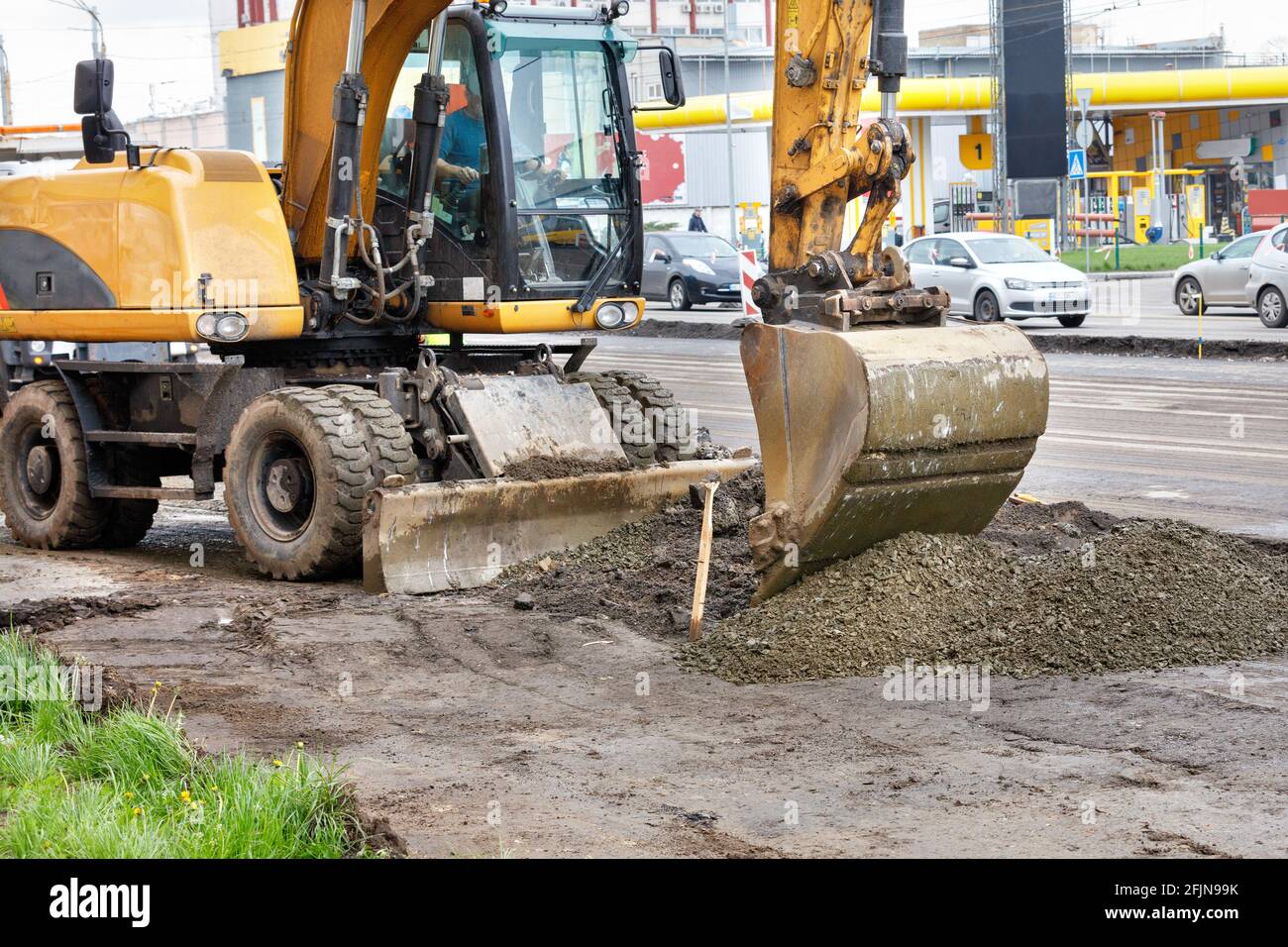 A heavy road excavator flattens a pile of rubble with a bucket when ...
