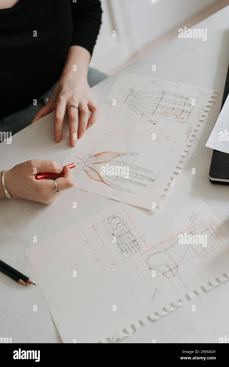 A vertical shot of female hands drawing human hand sketches on the ...