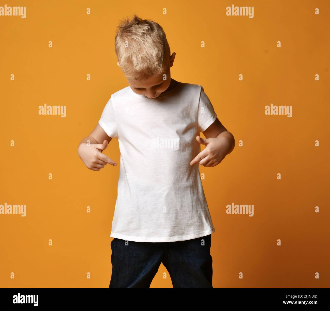 Blond boy child in white t-shirt and jeans standing and looking at ...
