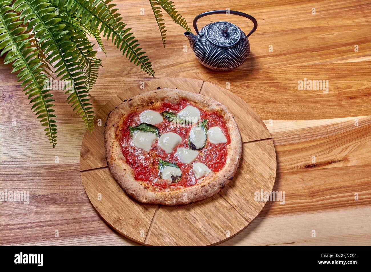 italian pizza margarita with basil and mozzarella on a wooden stand ...